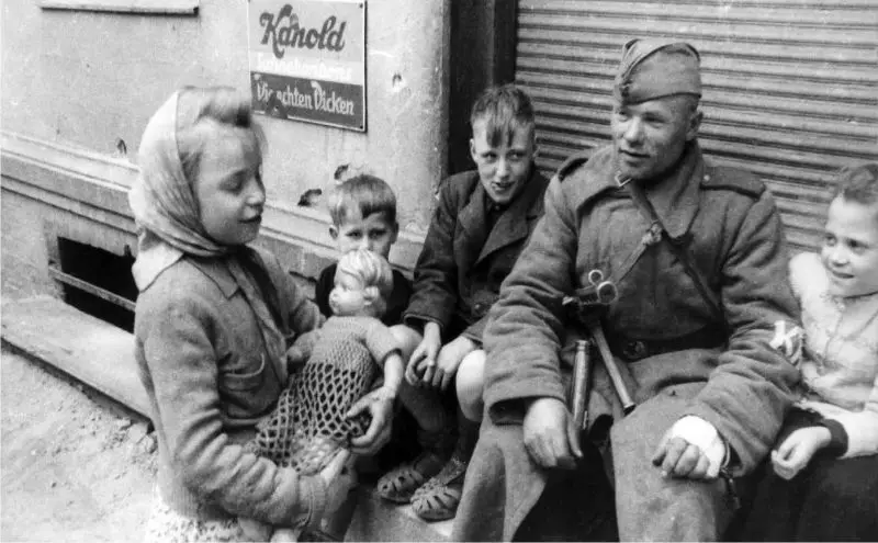 Sarkanais armijas ar vācu bērniem pie ieejas veikalā Berlīnē. 1945. gada maijs. Waralbum.ru.