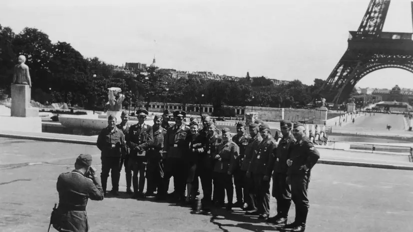 Luftwaffe Militionnel Personnel Posing Photographer manohitra ny fototry ny Eiffel Tower any Paris. Any afovoany dia misy tovovavy - angamba mpiasa amin'ny fitantanan-draharaha miasa. 1940 taona